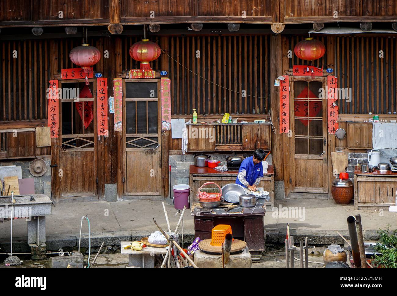 open air cooking in the courtyard of a Tulou (building made of rammed ...