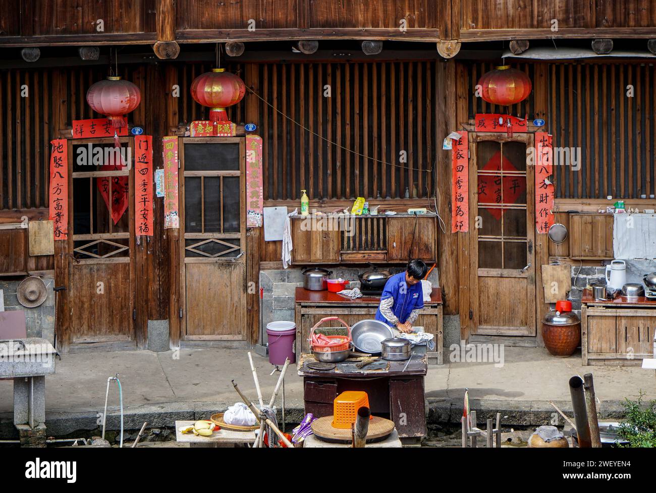 open air cooking in the courtyard of a Tulou (building made of rammed ...