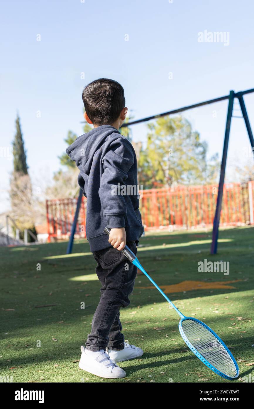 Back View Of A Young Child Holding A Badminton Racket In A Park, Ready ...