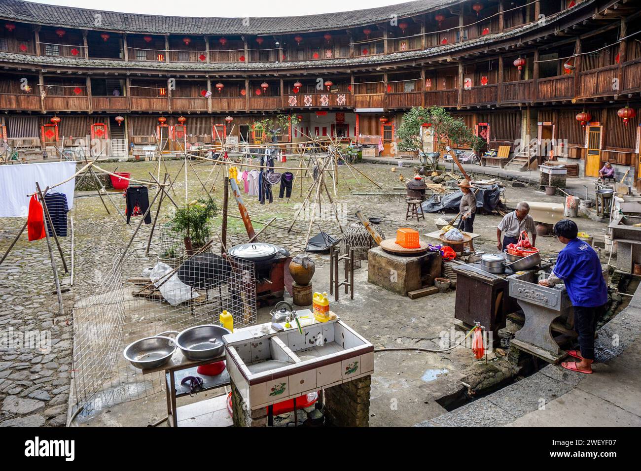 open air cooking in the courtyard of a Tulou (building made of rammed ...