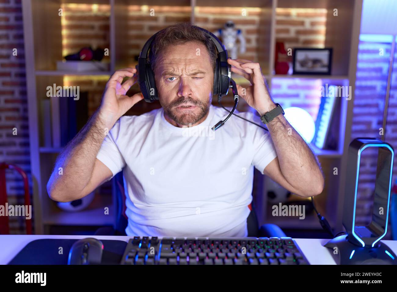 Middle age man with beard playing video games wearing headphones ...