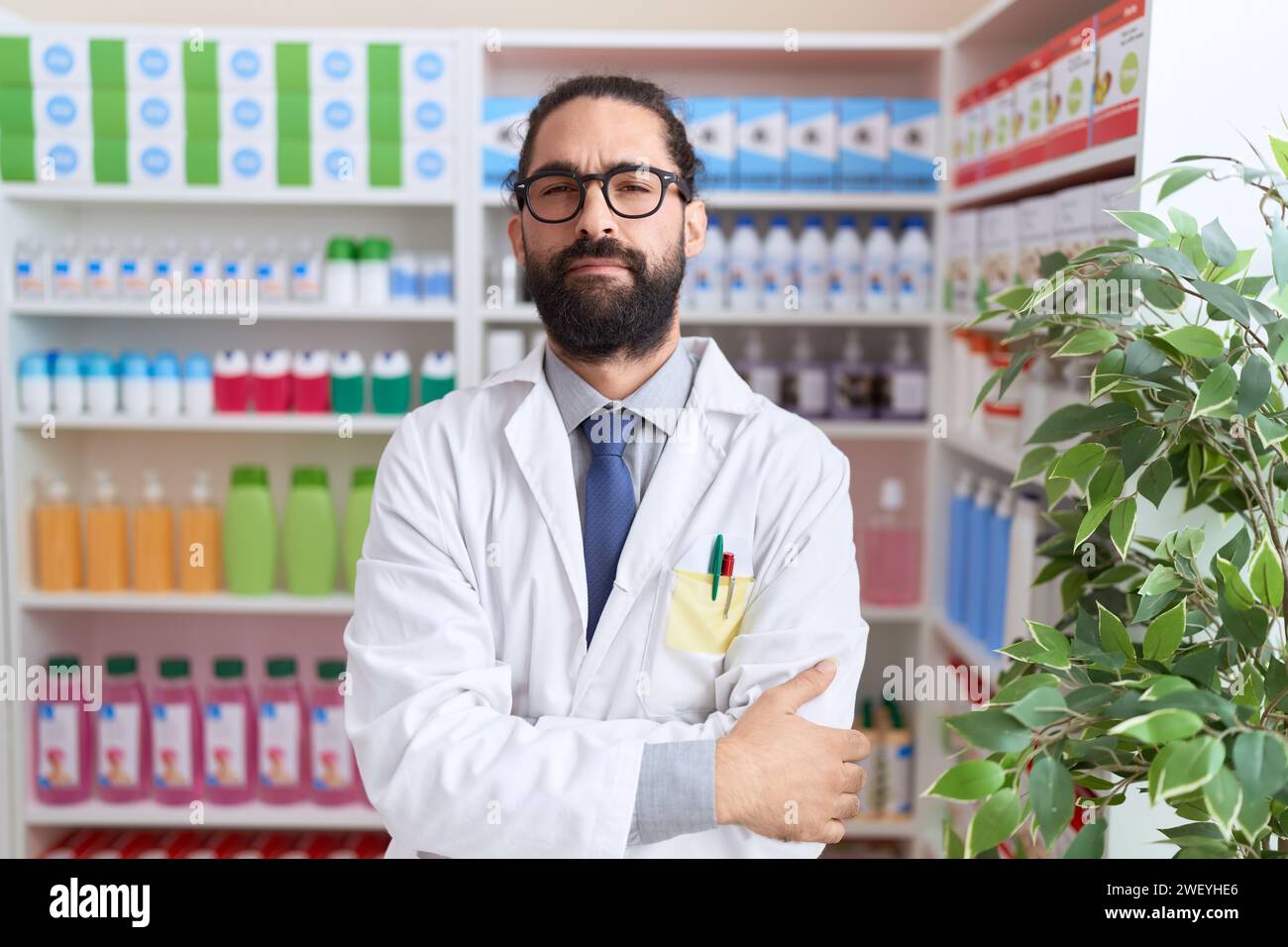 Hispanic man with beard working at pharmacy drugstore skeptic and ...