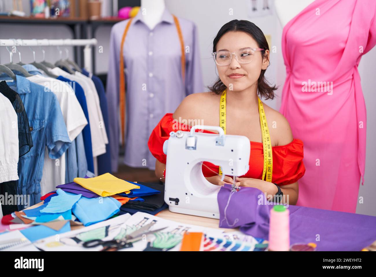 Hispanic young woman dressmaker designer using sewing machine smiling ...