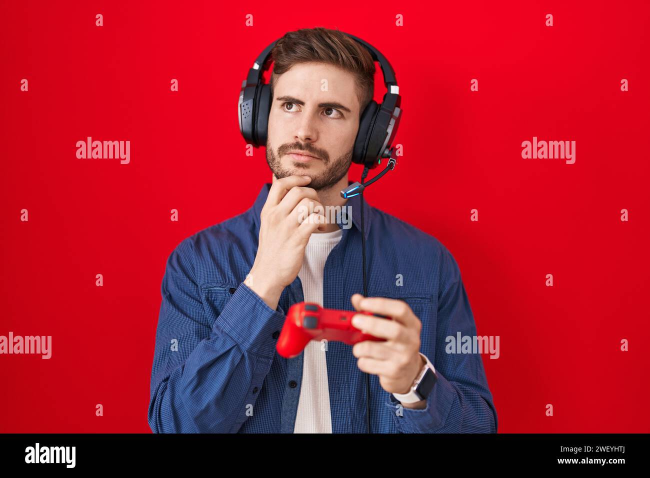 Hispanic man with beard playing video game holding controller serious ...