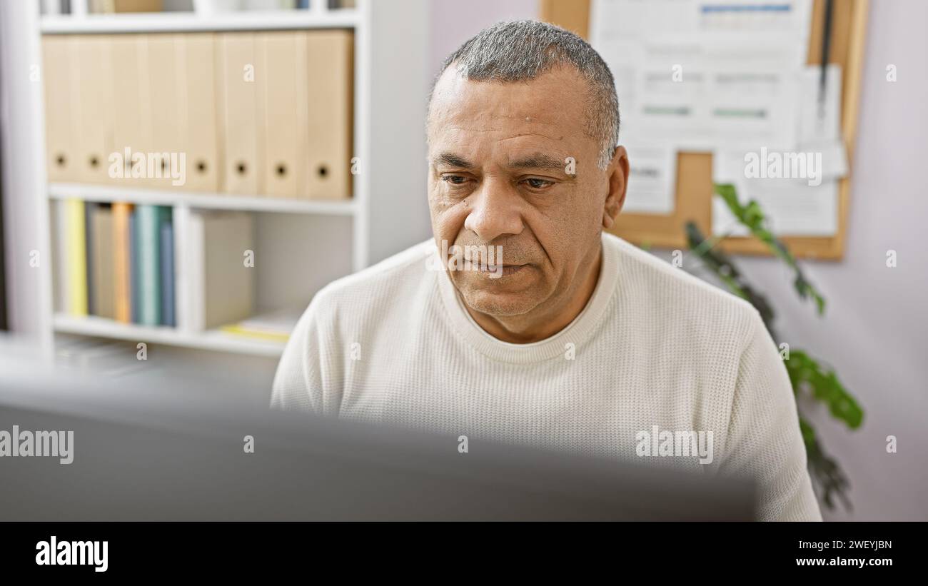 A middle-aged hispanic man working at his office with shelves and ...