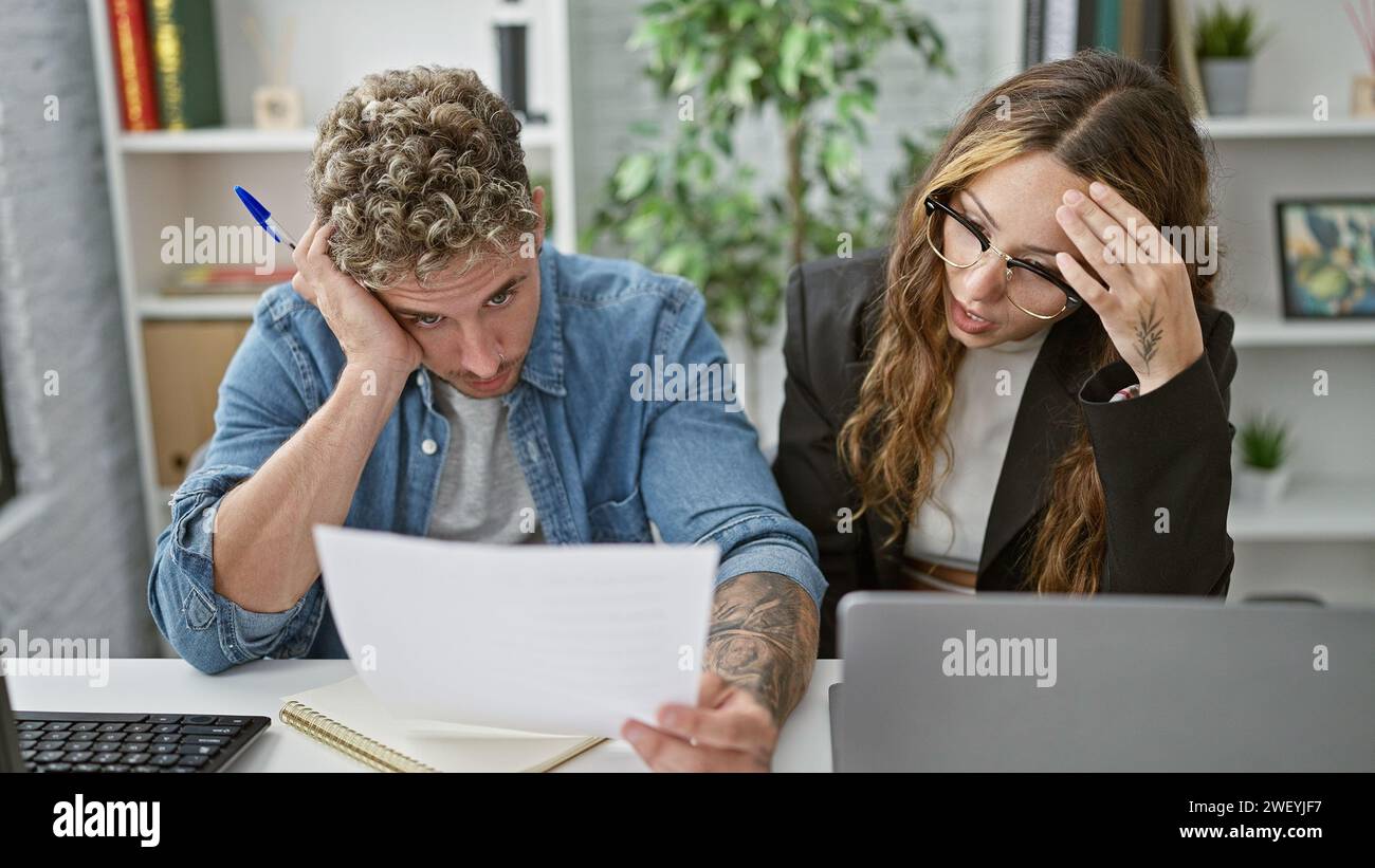 A stressed man and woman evaluate a document together in a modern ...