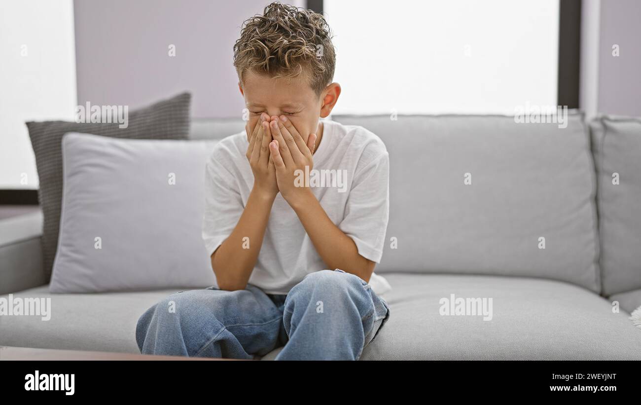 Adorable blond boy crying on sofa, unhappy child struggling with ...