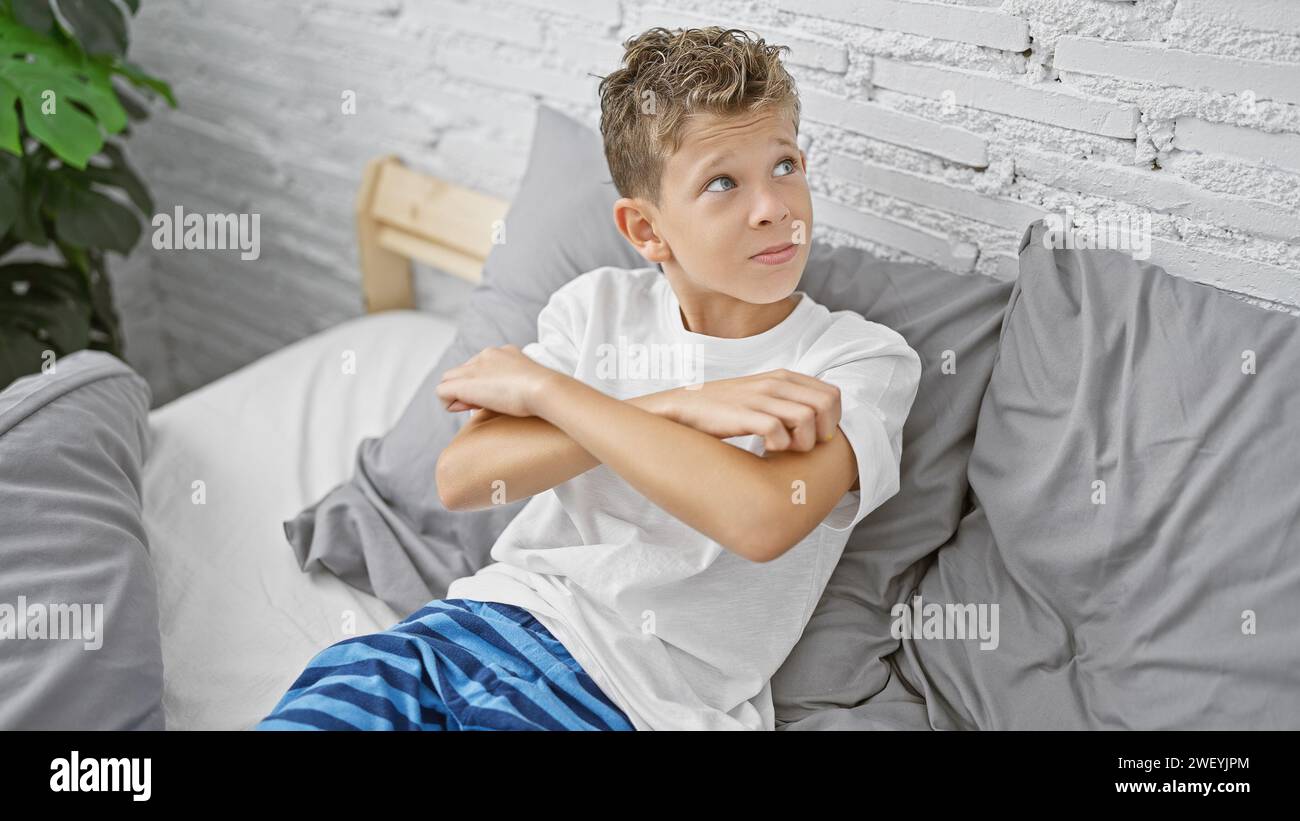 Adorable blond boy sitting in bedroom, scratching itchy arm rash ...