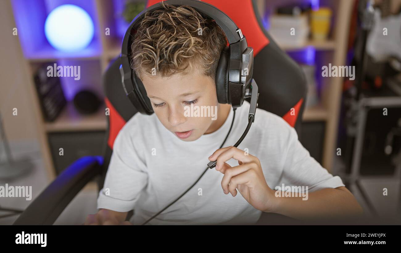 Blond boy streamer playing video game using computer at gaming room ...