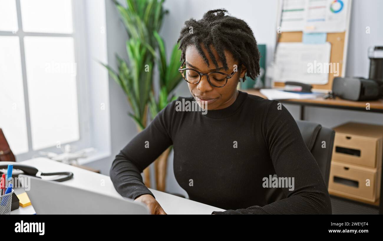 Focused african american woman with dreadlocks working on a laptop in a ...