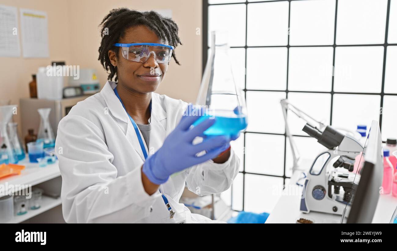 African woman scientist examining a flask in modern laboratory setting ...