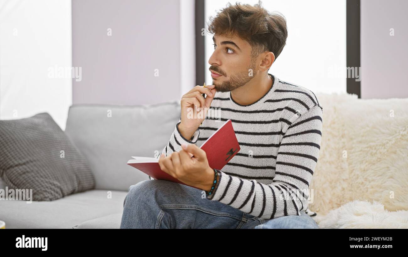 Smart, handsome young arab man, doubtful yet studying with comfort on his living room sofa ...