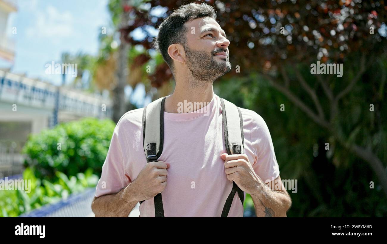 Young hispanic man tourist wearing backpack looking around smiling at ...