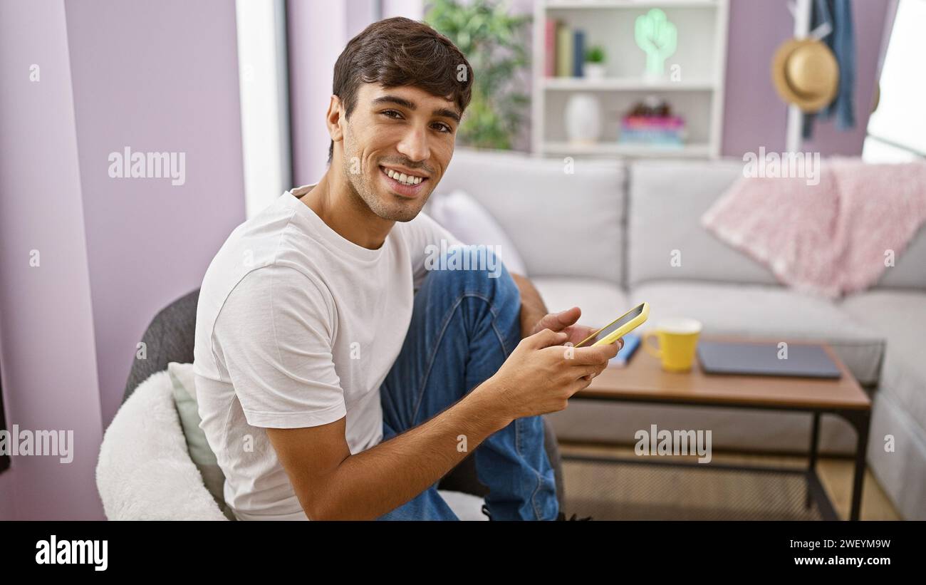 Radiant young hispanic man sitting at home, having a blast texting on ...