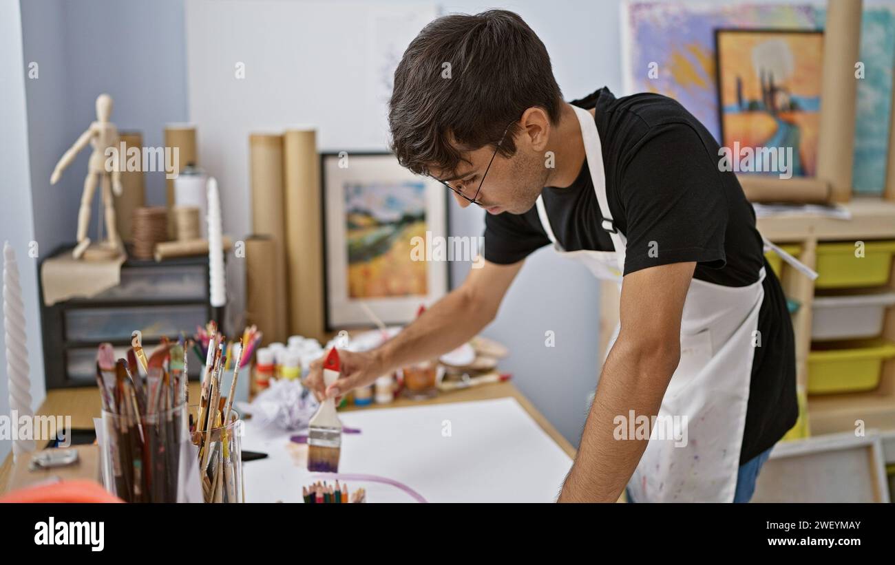 Young, handsome hispanic man seriously concentrating on drawing art in ...