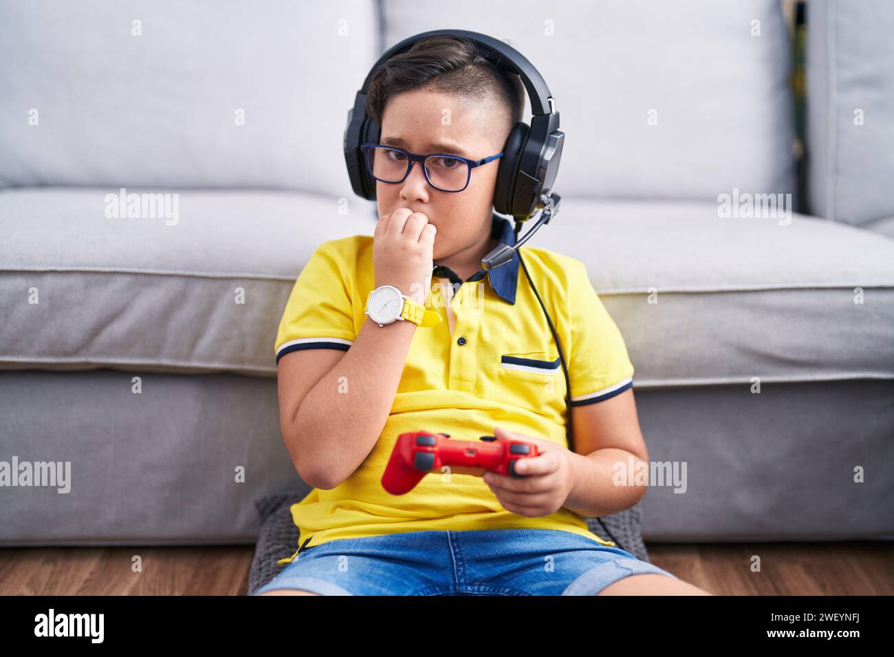 Young hispanic kid playing video game holding controller wearing ...
