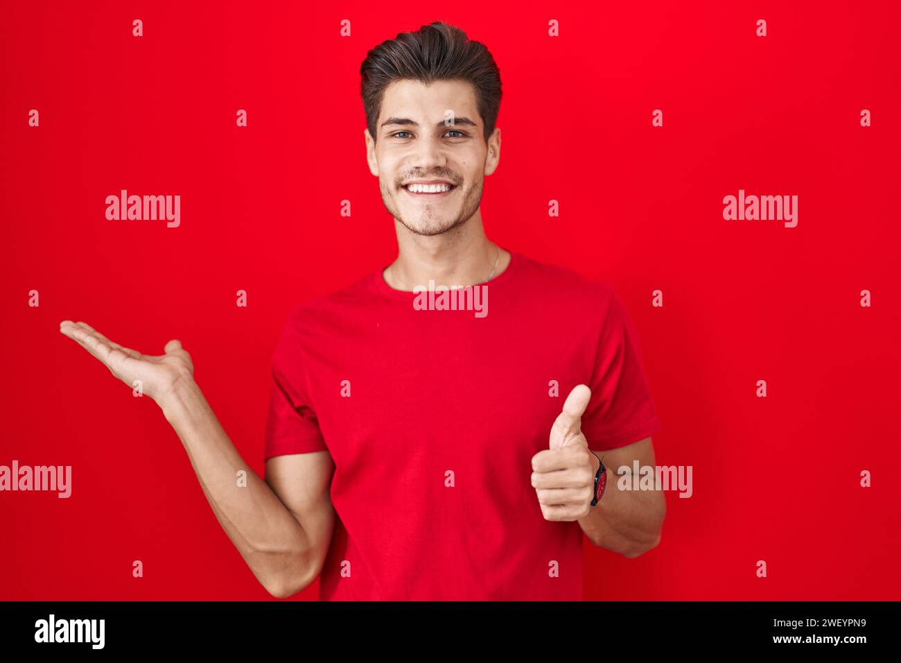 Young hispanic man standing over red background showing palm hand and ...