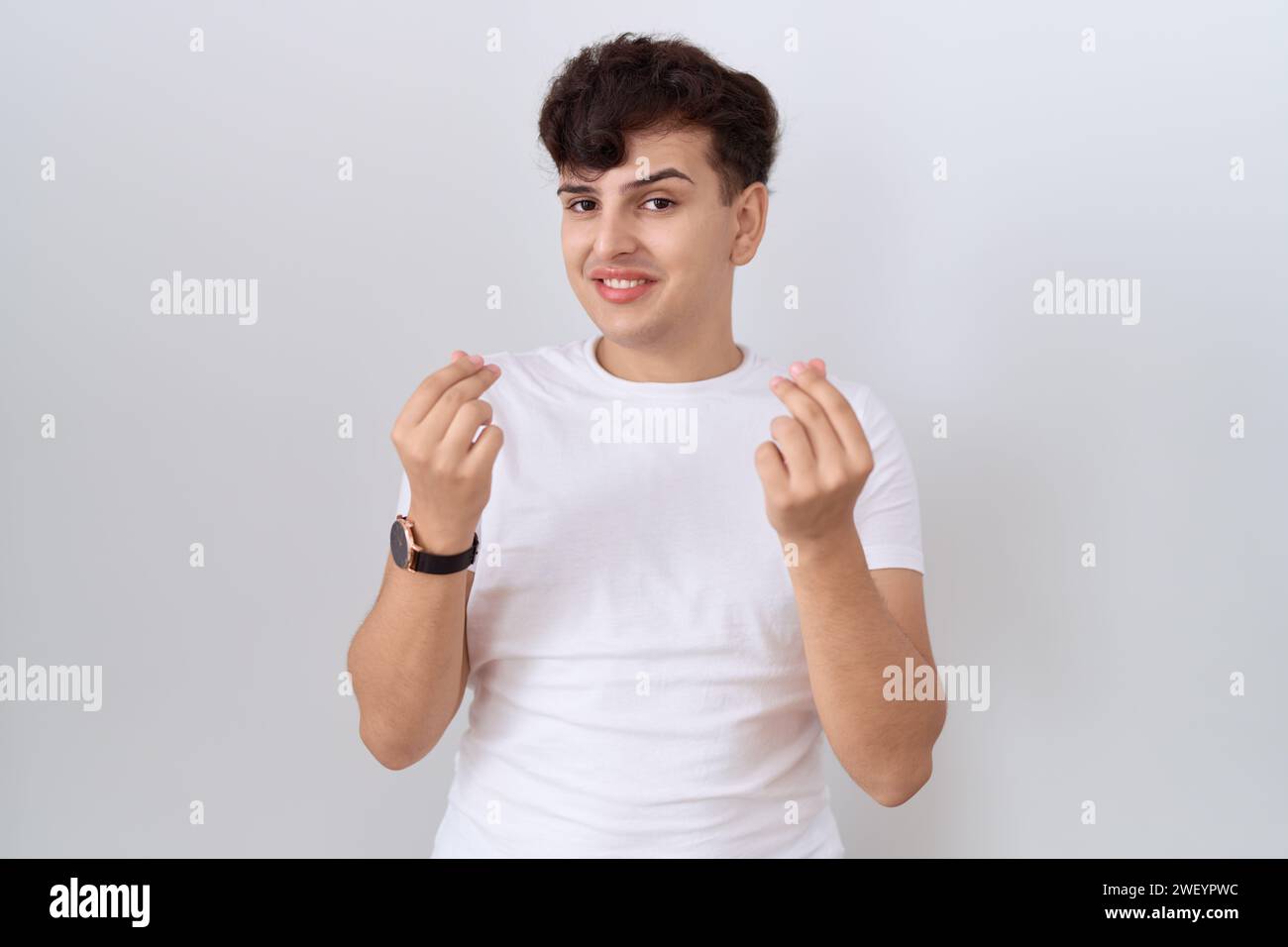 Young non binary man wearing casual white t shirt doing money gesture ...