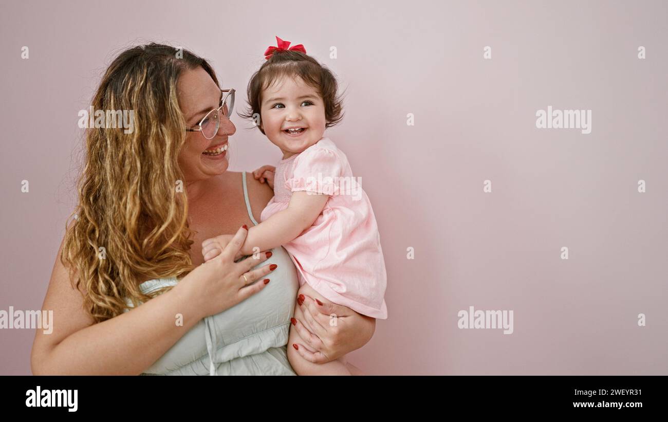 Confident mother joyfully holding her cute baby daughter in her arms ...