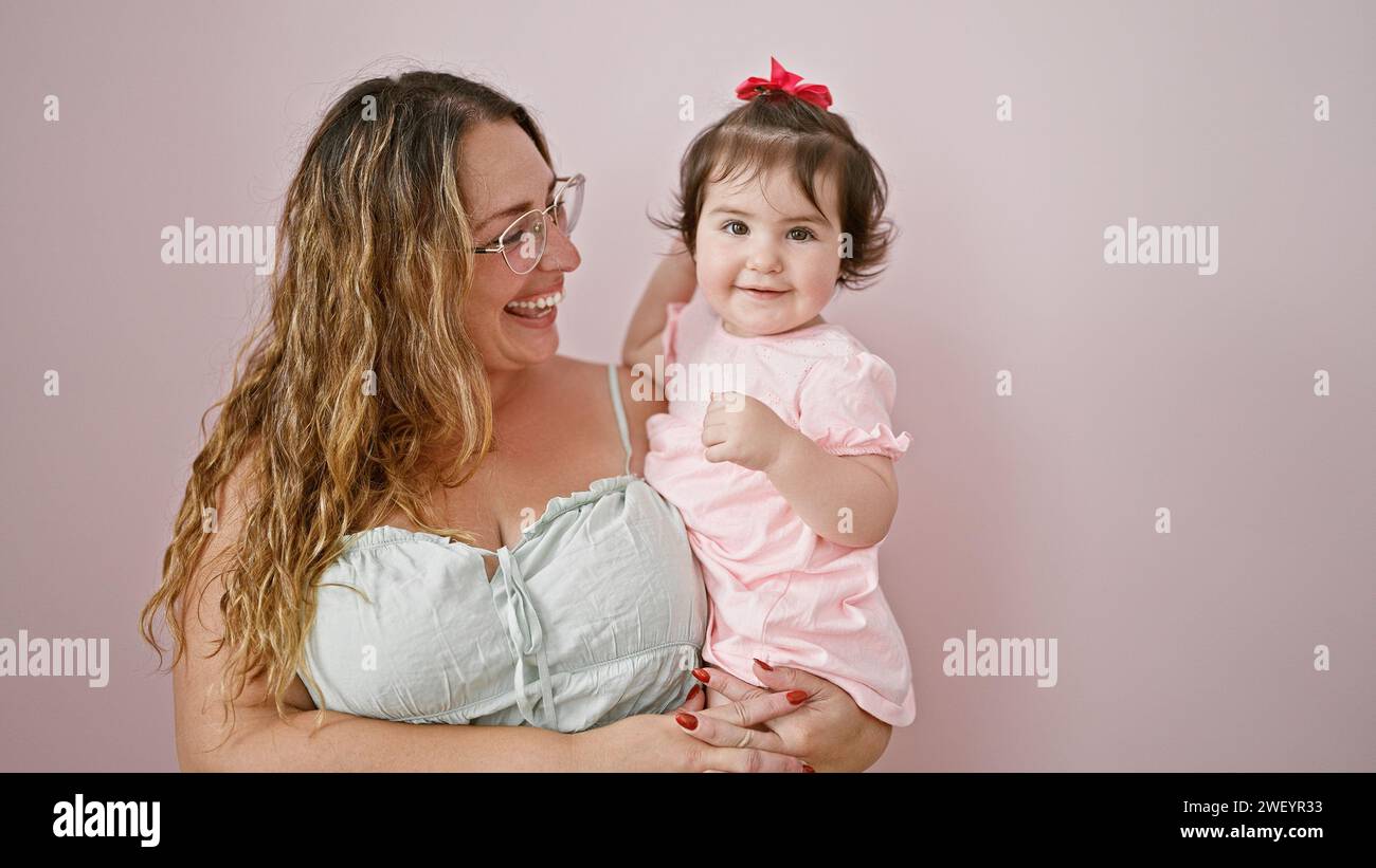 Confident mother joyfully holding her cute baby daughter in her arms ...