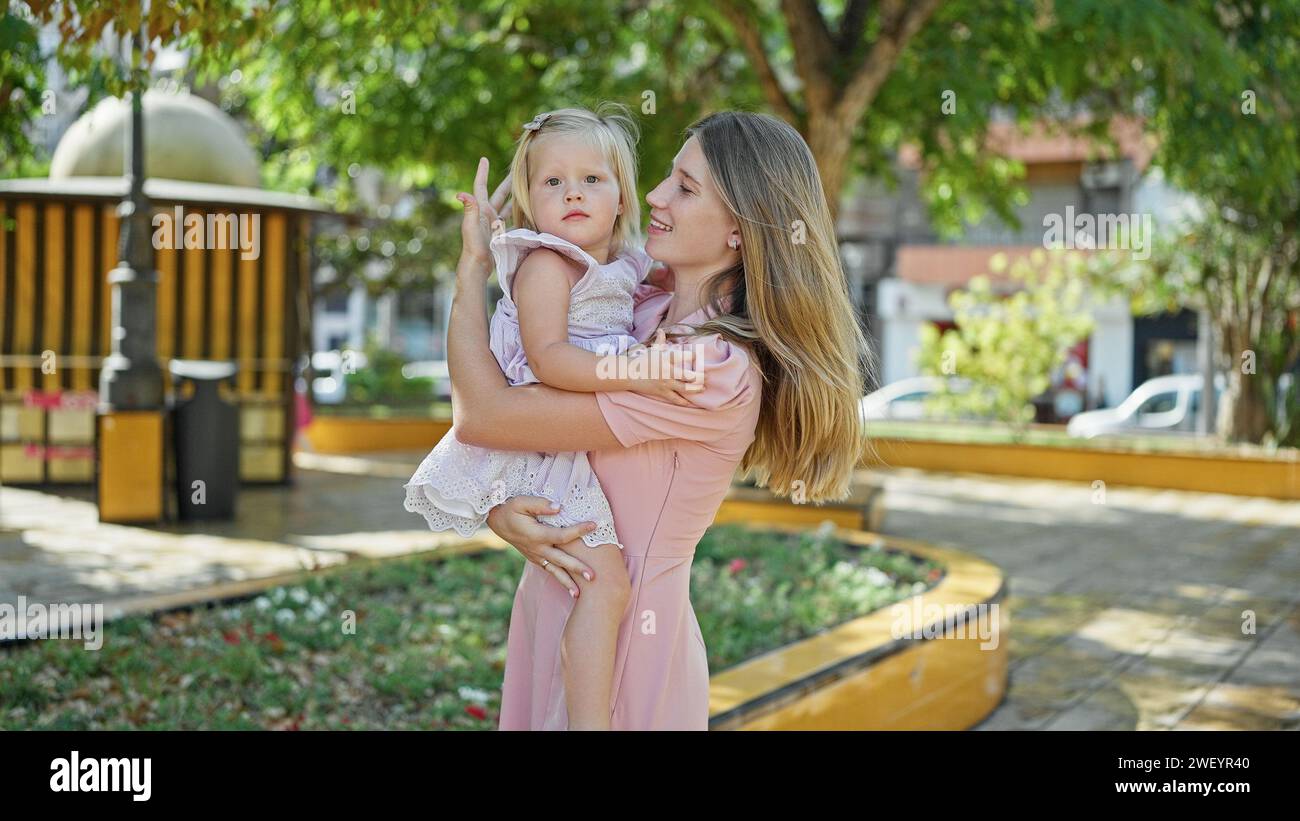 Confident mother, arms wrapped around her daughter, smiling joyfully ...