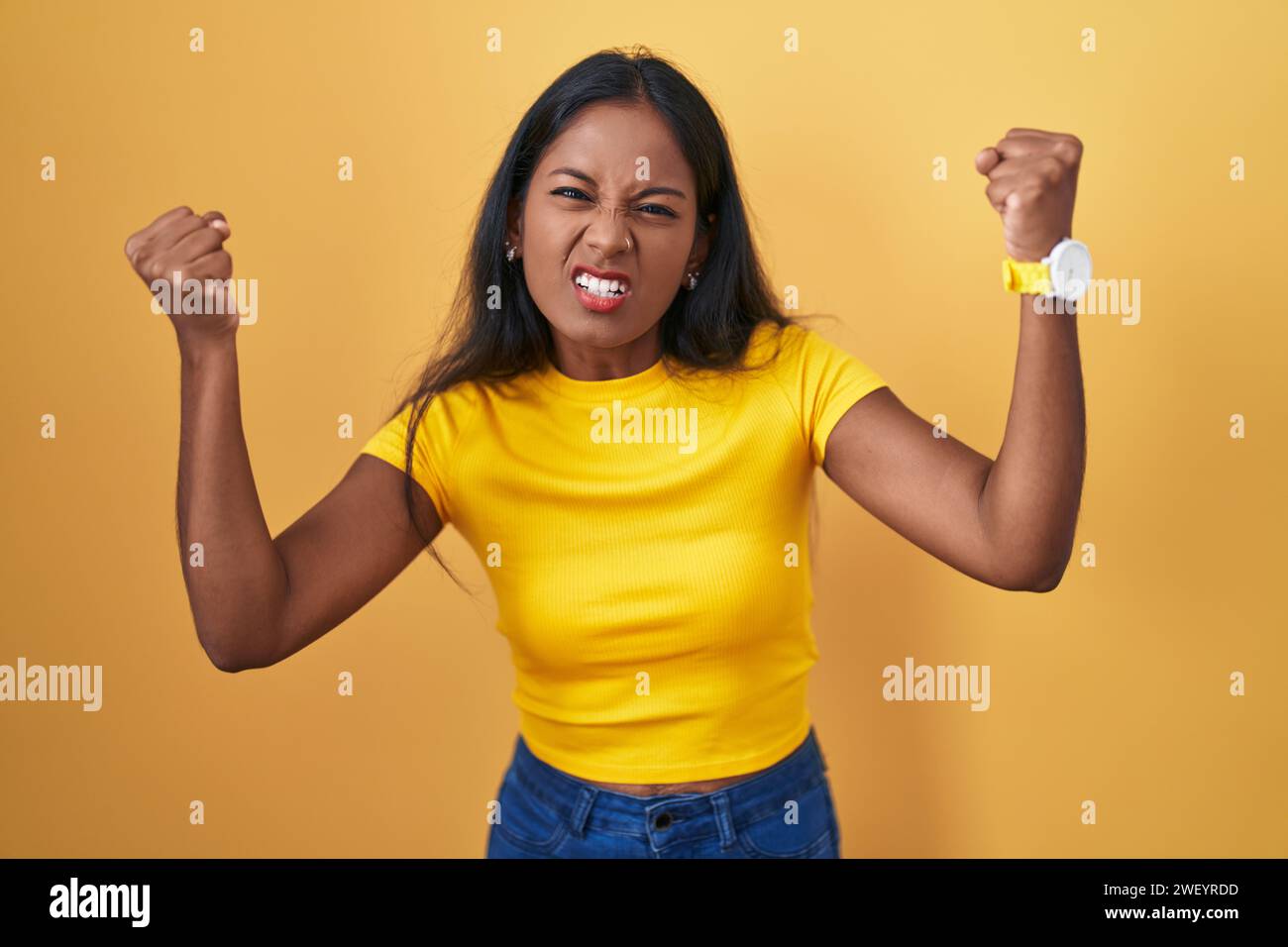 Young indian woman standing over yellow background angry and mad ...
