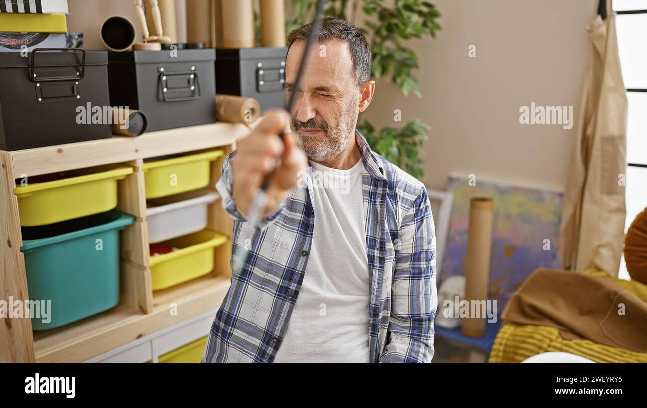 Mature artist man, with grey hair, seriously holding his paintbrush ...