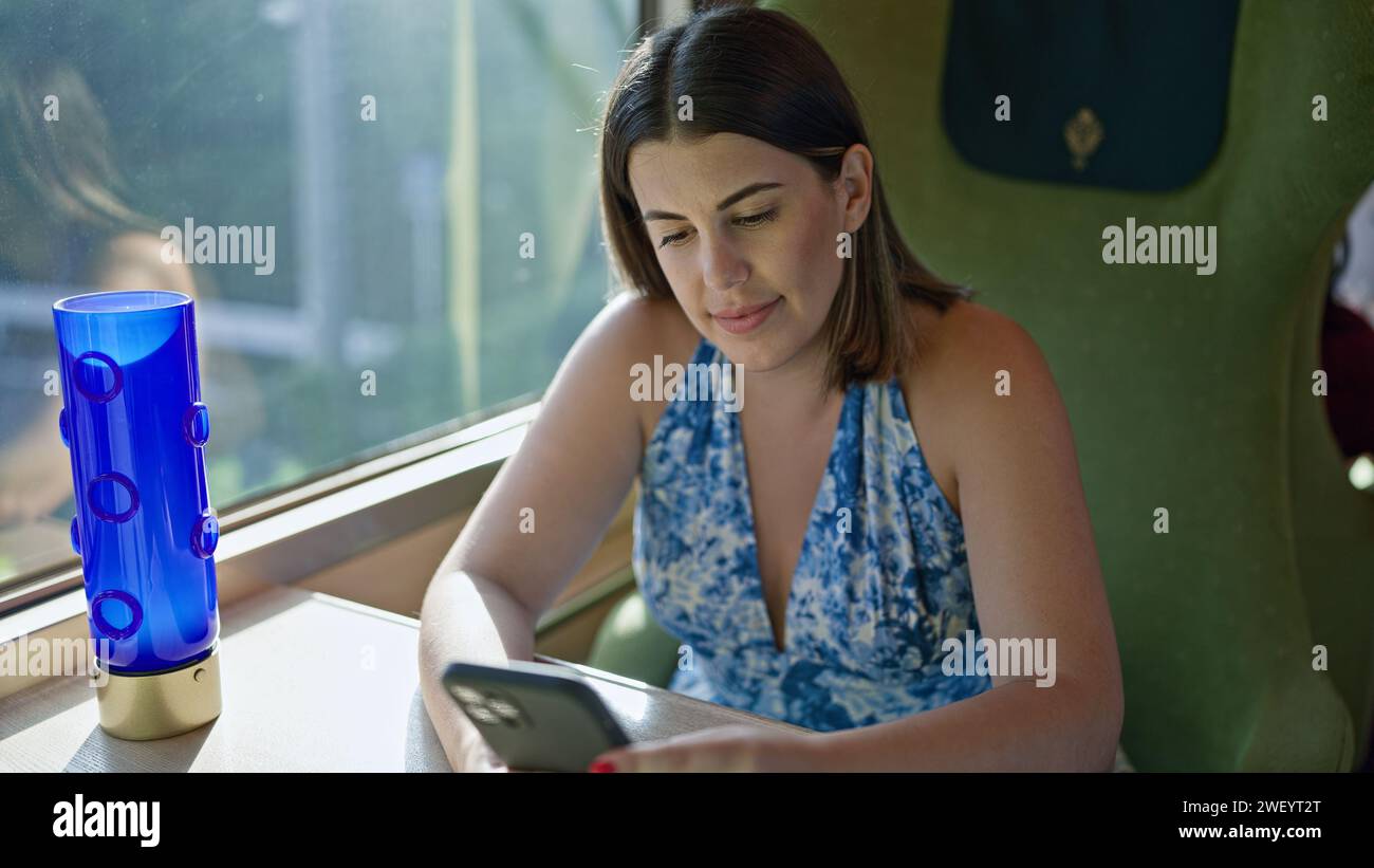 Smiling beautiful hispanic woman sitting, happily texting on her ...