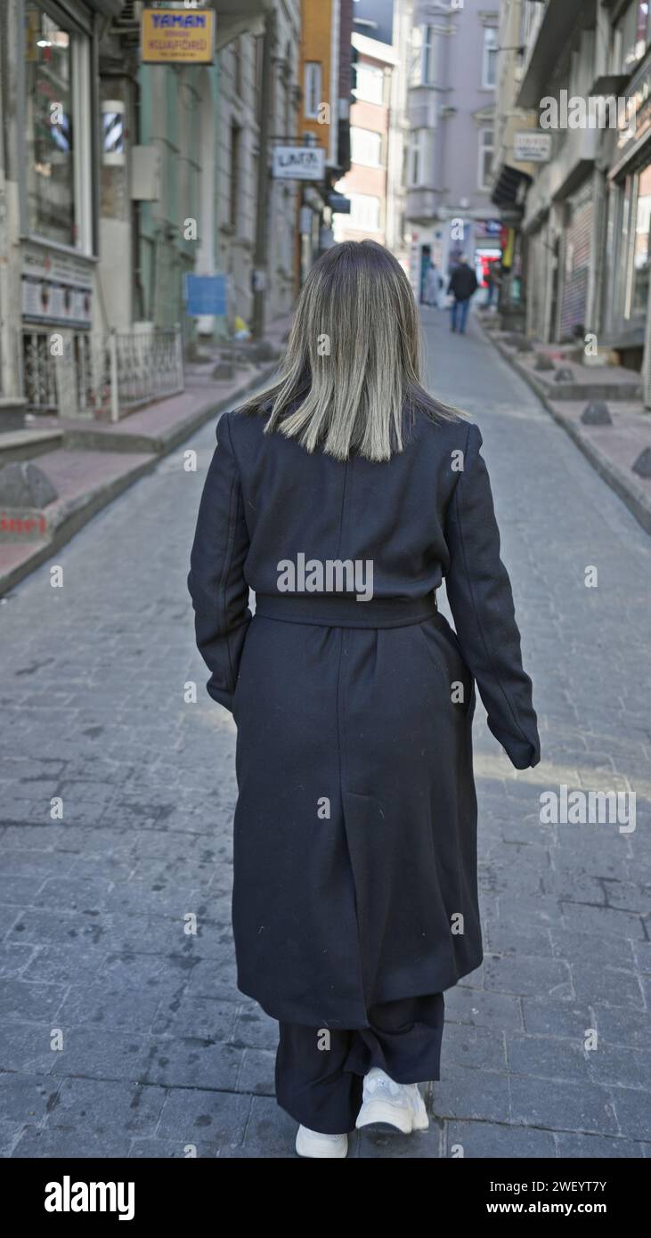 Back view of a young woman walking alone on a historic istanbul street ...