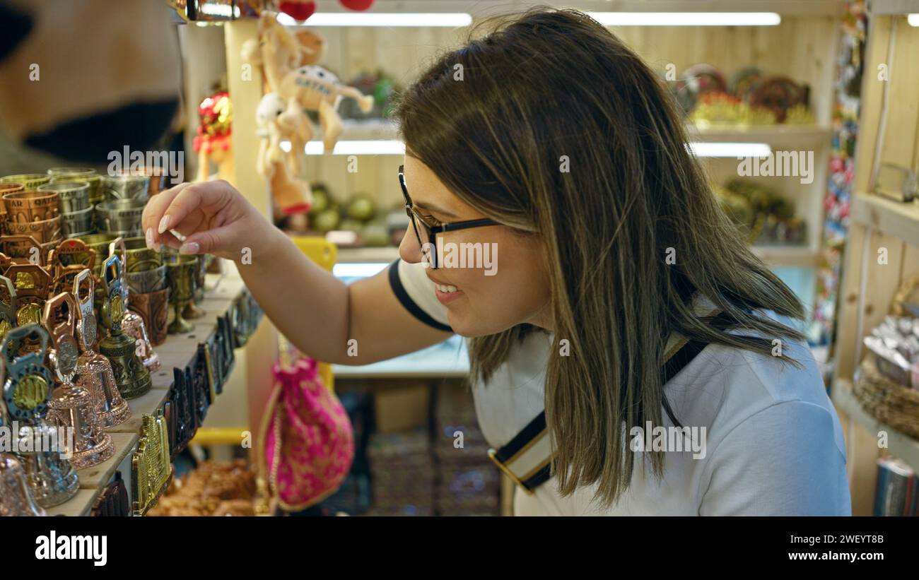 A young adult hispanic woman shops at souq waqif, doha, examining ...