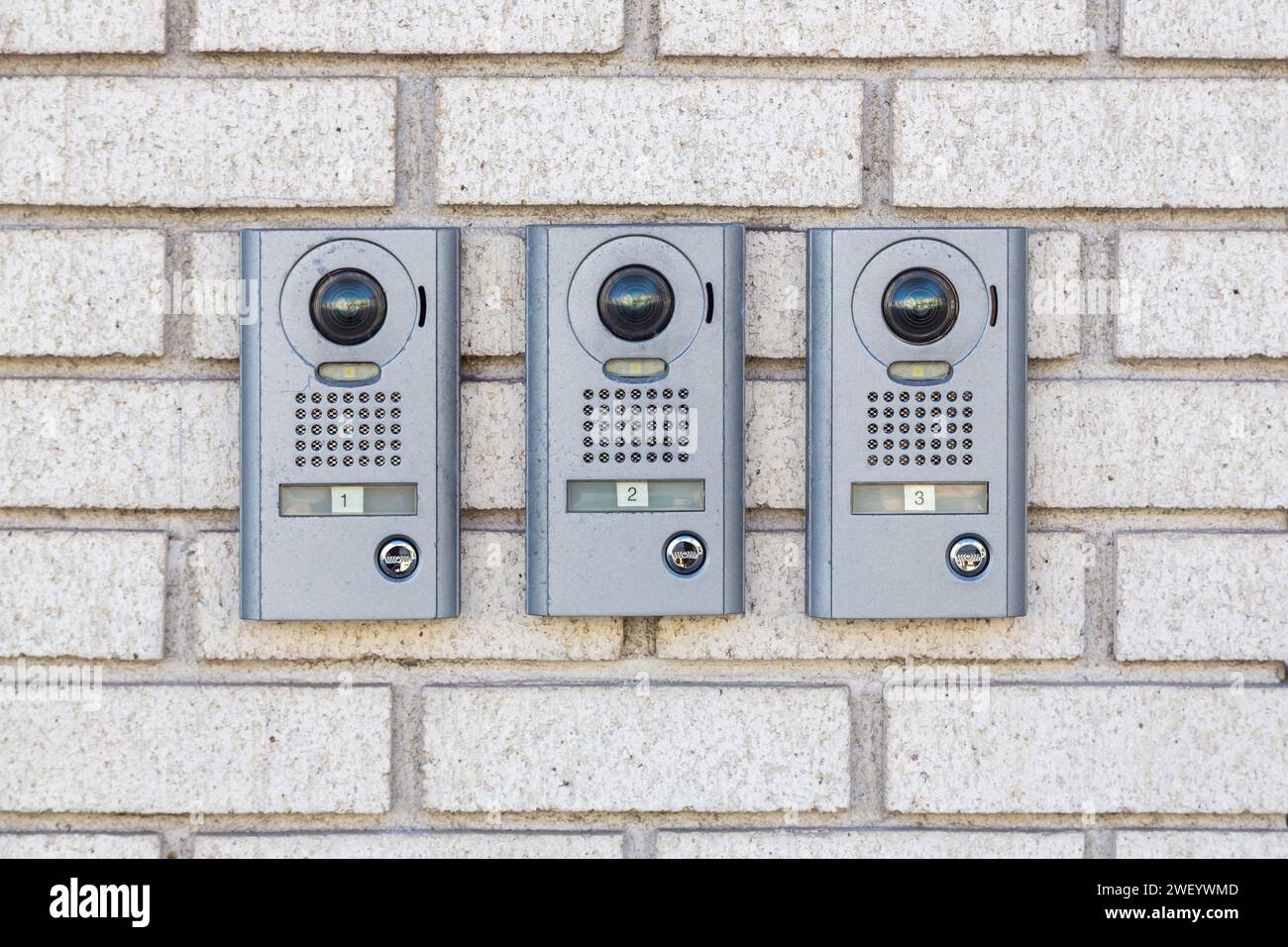 Three intercom on white textured brick wall, Close up. Apartment ...
