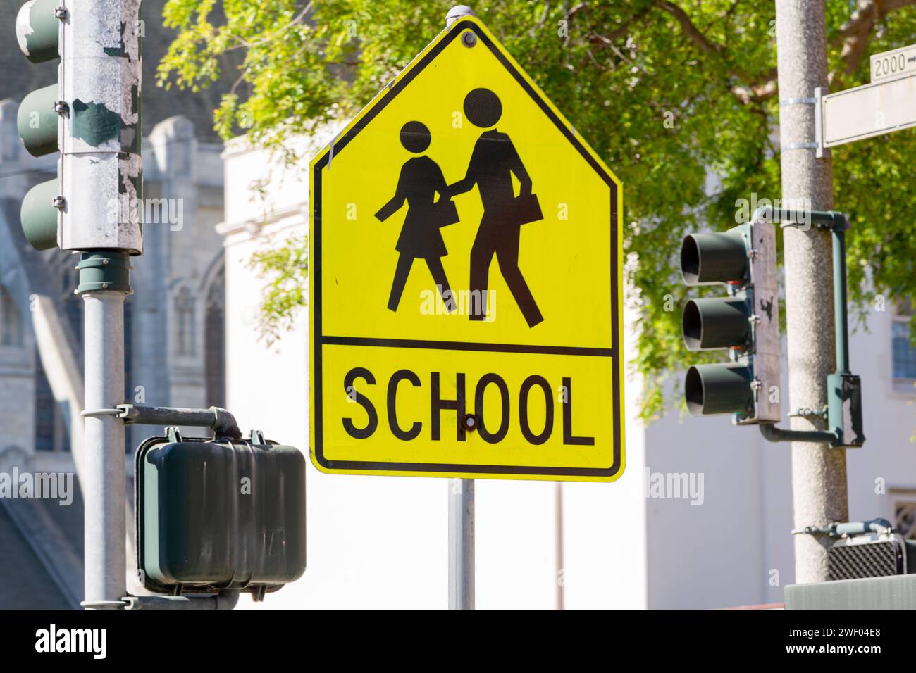 Yellow warning road sign for a school zone at a road intersection with ...