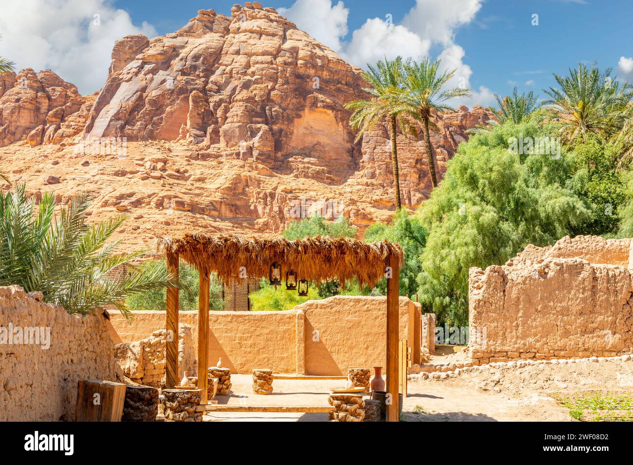 Al Ula ruined old town streets with straw sunshade tent and palms with ...