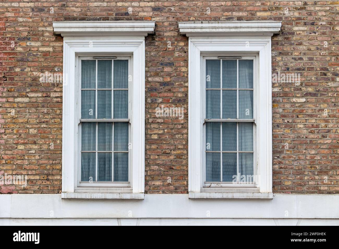 two classic white windows of typical london architecture with red brick ...