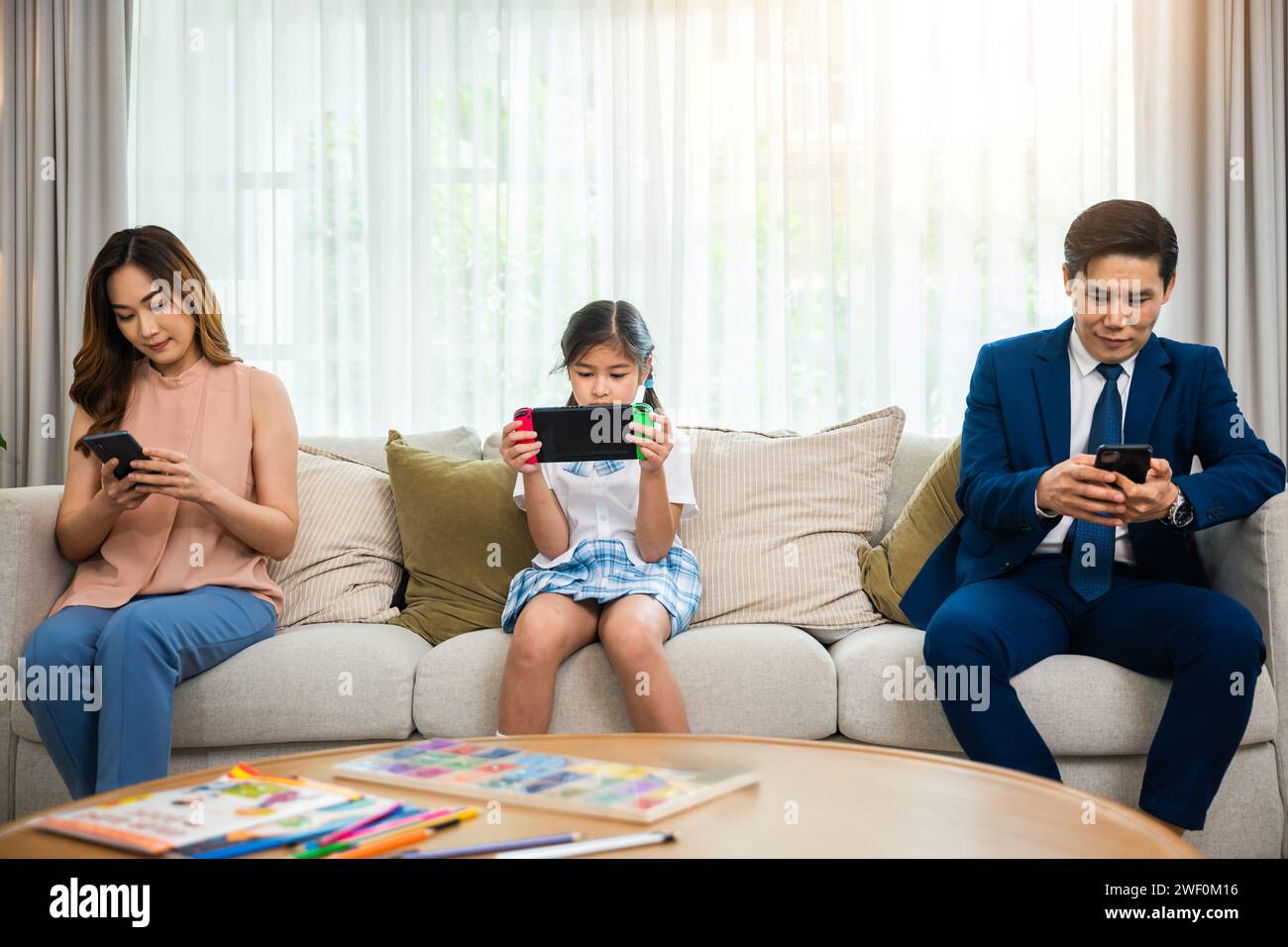 Asian parents ignore their child and looking at their mobile phone at ...