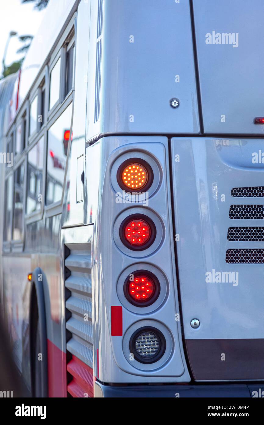 Close-up of rear glowing brake lights of a city bus standing at a ...