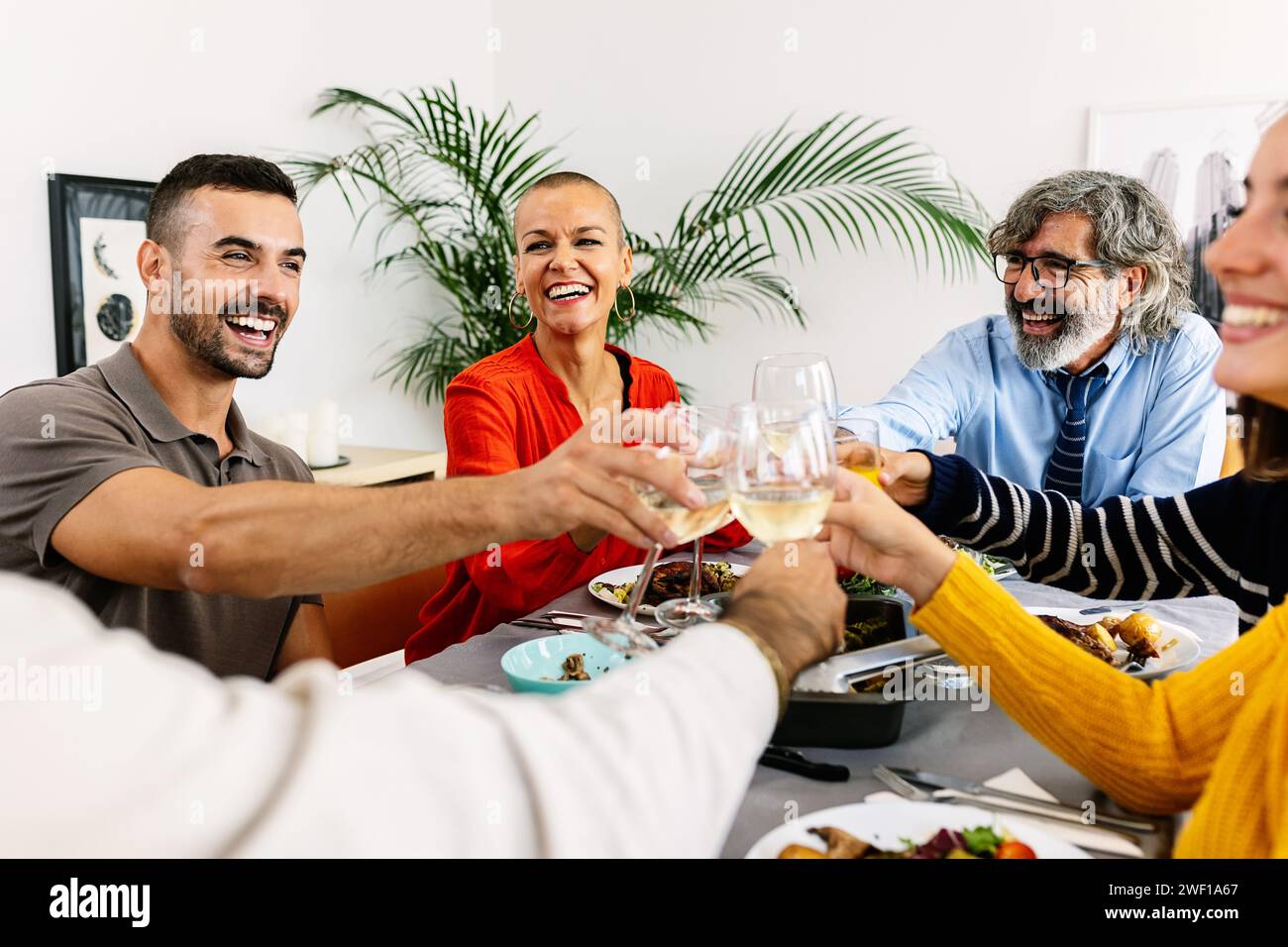 Happy group of multi-generational family toasting wine at dinner party ...