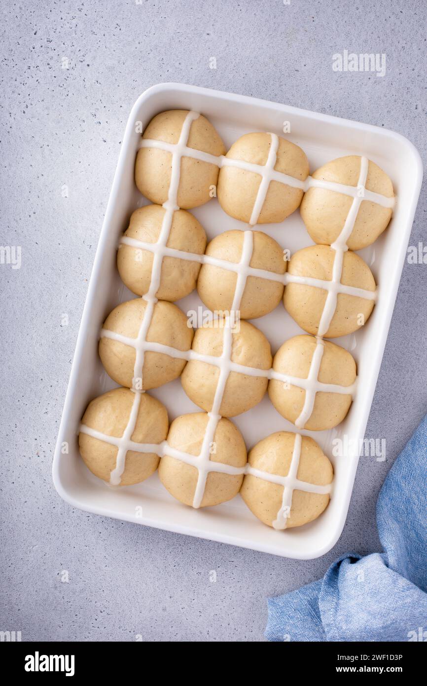 Hot cross buns ready to be baked in a pan with cross pattern on top ...