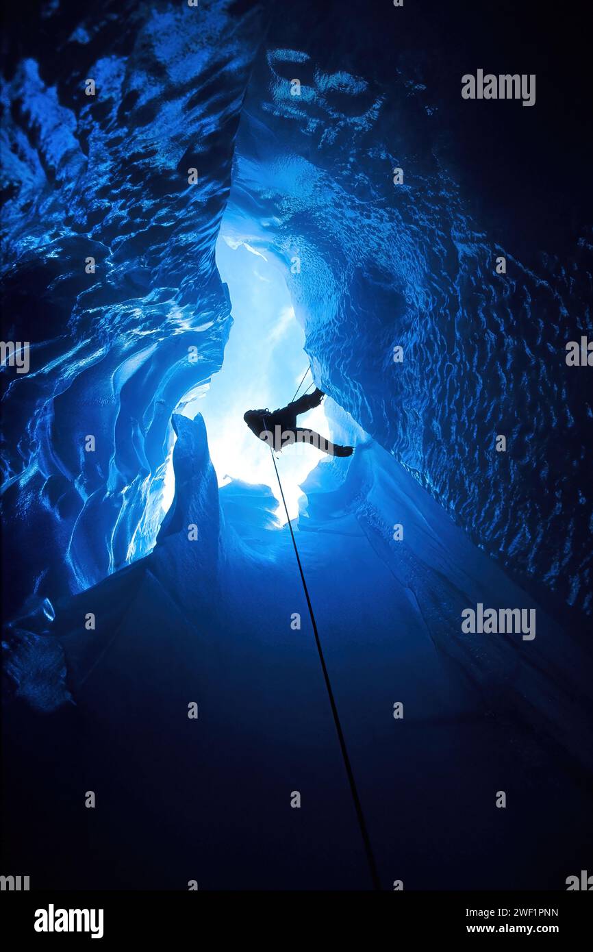 Caver abseiling (rappelling) into an ice cave shaft on the Fox Glacier ...