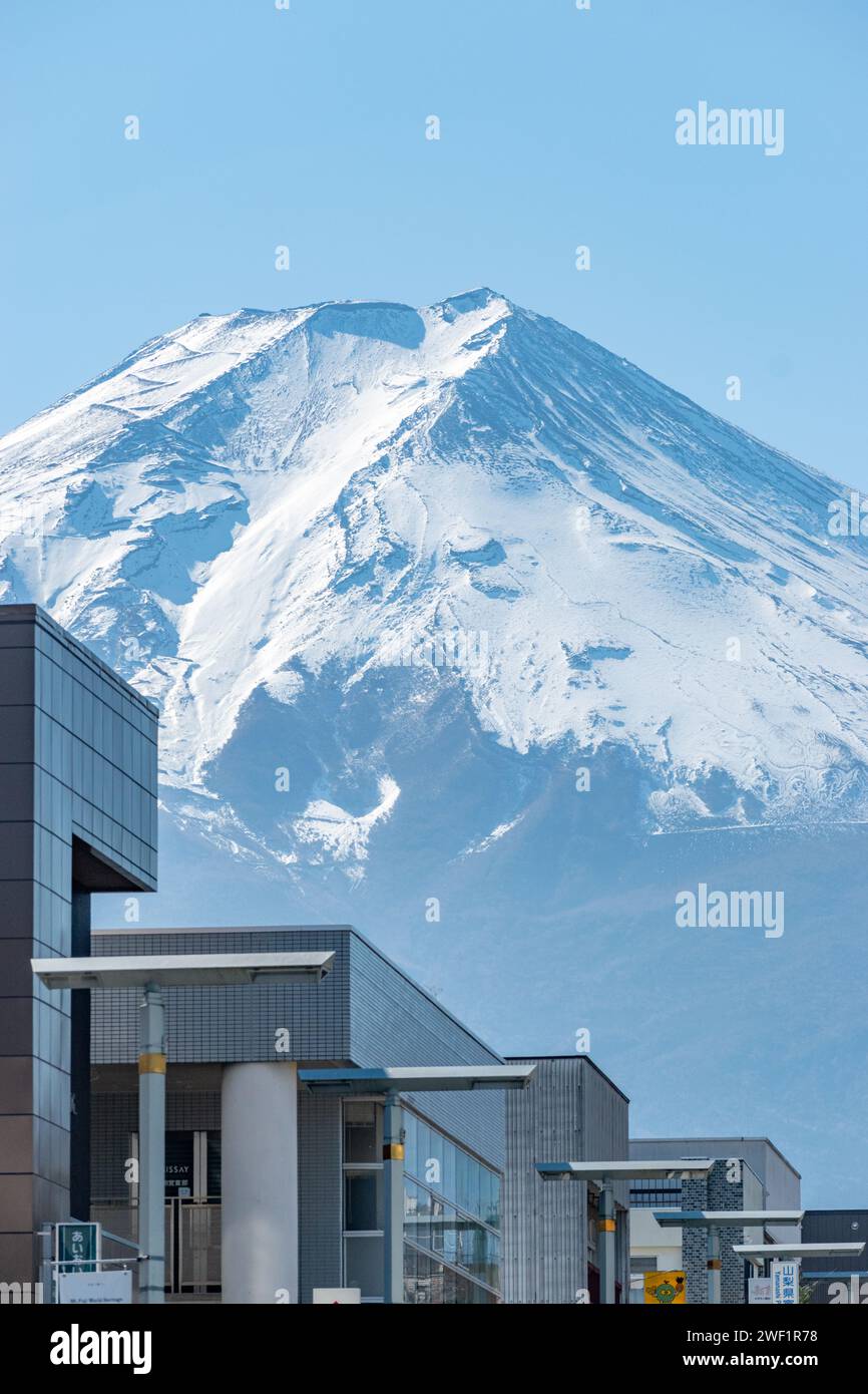 A large, looming snow-capped Mount Fuji above the buildings of ...