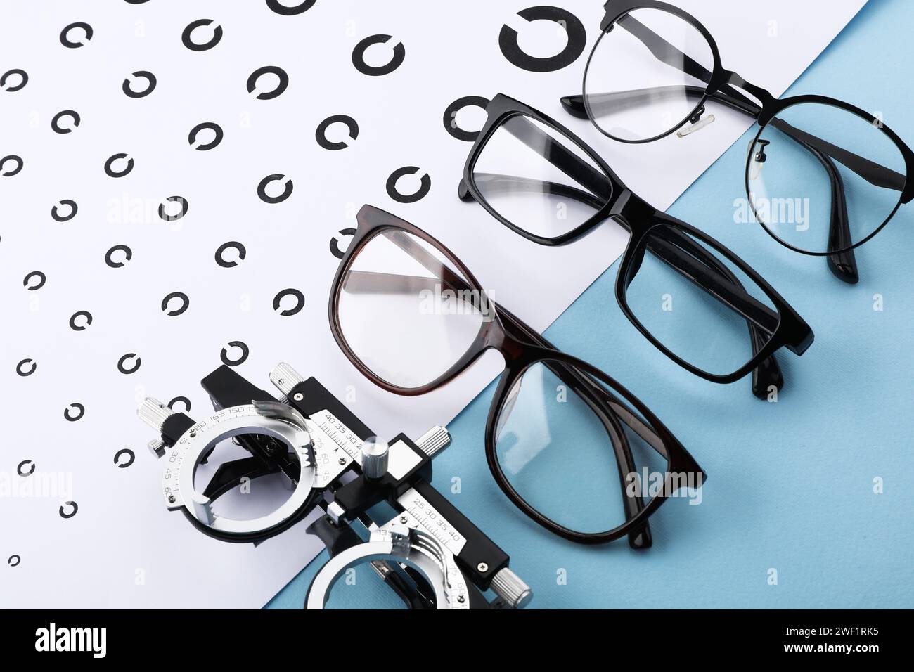 Vision test chart, glasses and trial frame on light blue background ...