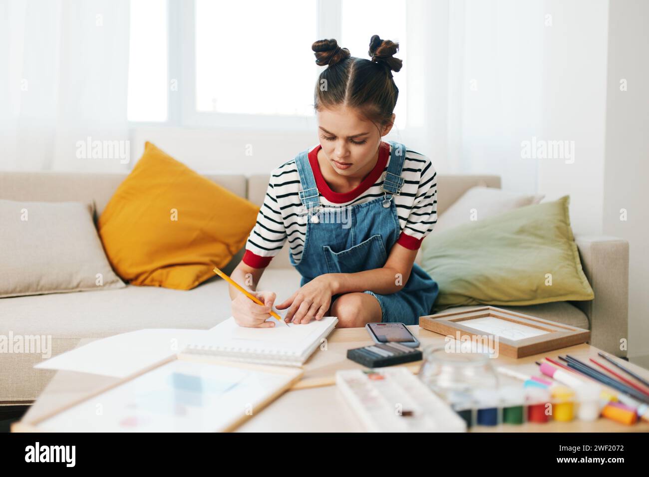 Happy teenage girl, a budding artist, painting a cute portrait at home ...