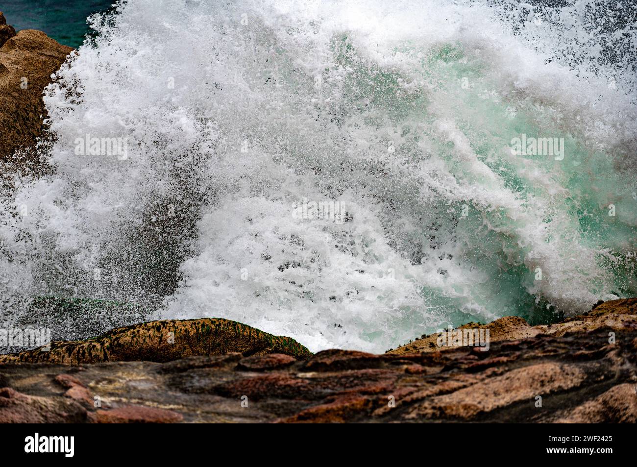powerful waves relentlessly crash against rugged boulders and stones ...