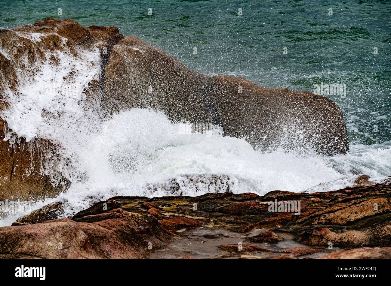 powerful waves relentlessly crash against rugged boulders and stones ...