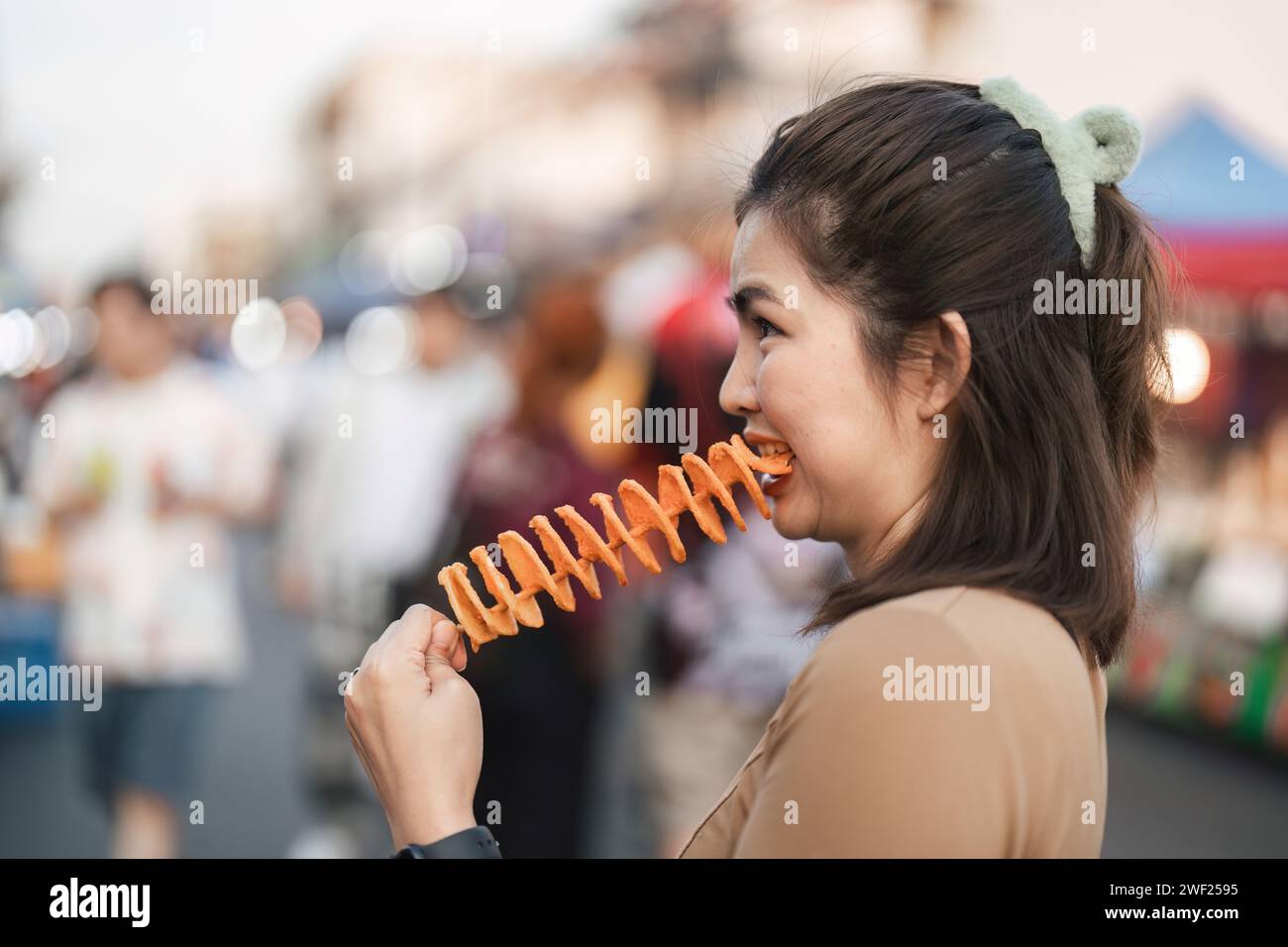 Happy young Asian Traveler foodie woman enjoy eating Tornado potatoes ...