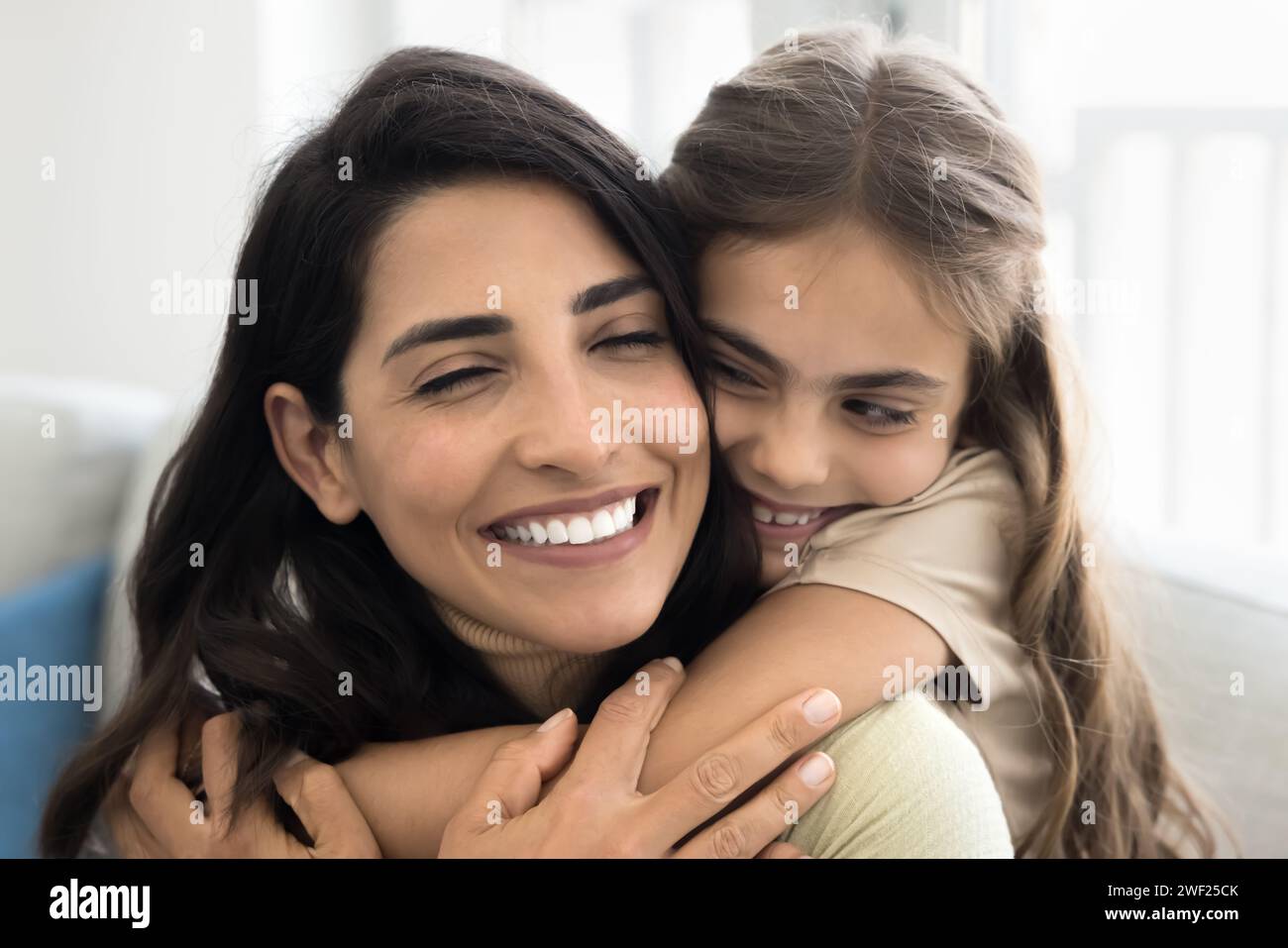 Cheerful cute daughter kid embracing happy mom from behind Stock Photo ...
