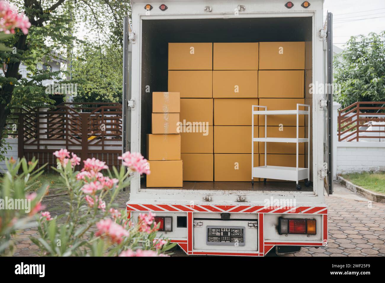 Moving cardboard boxes in an open car trunk outdoors. White delivery ...