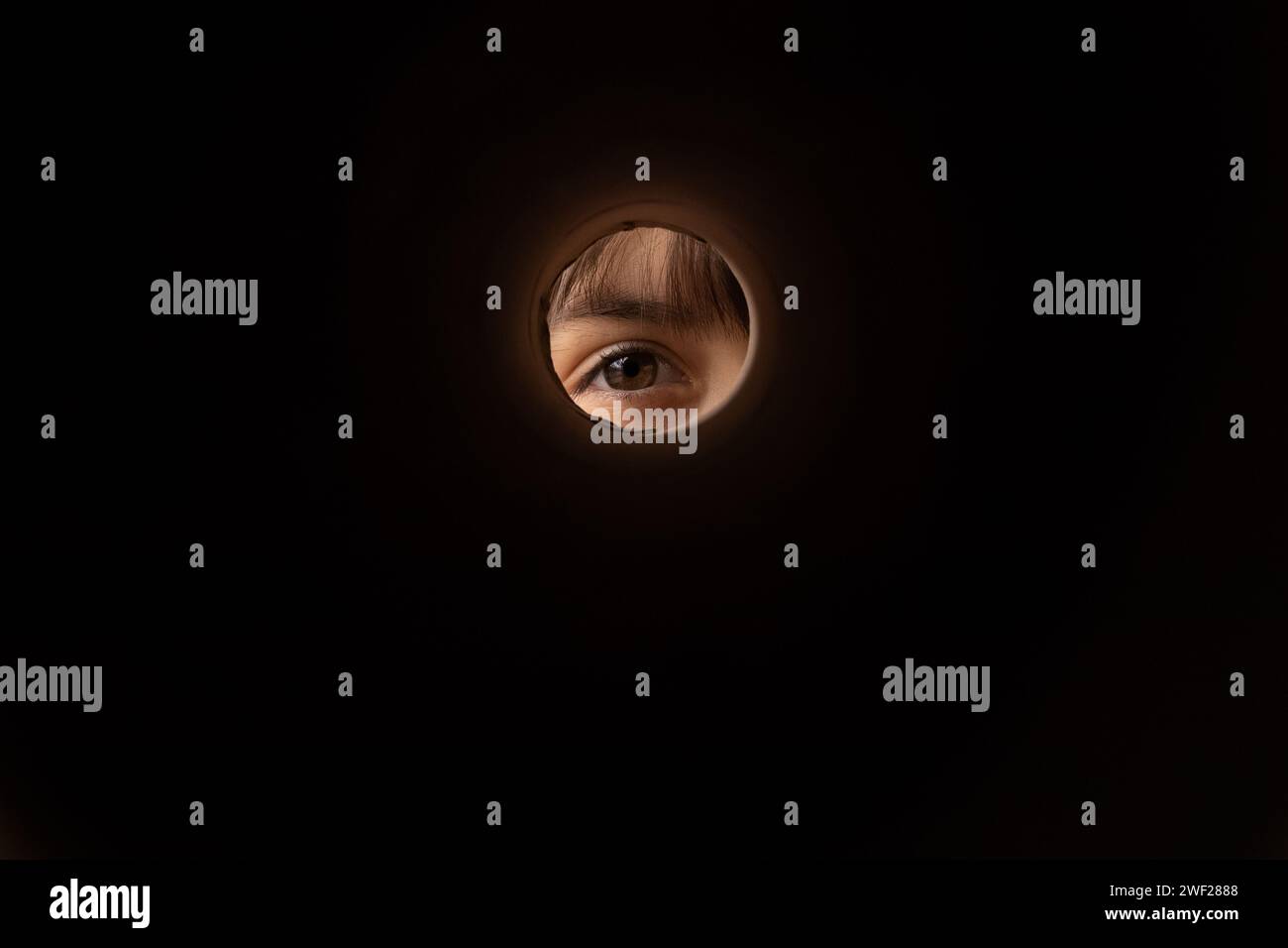 Curious little kid eye looking into box through round hall Stock Photo ...