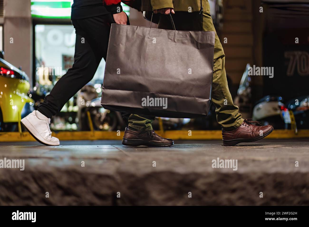 Two people walking through the city at night, one carrying a large ...