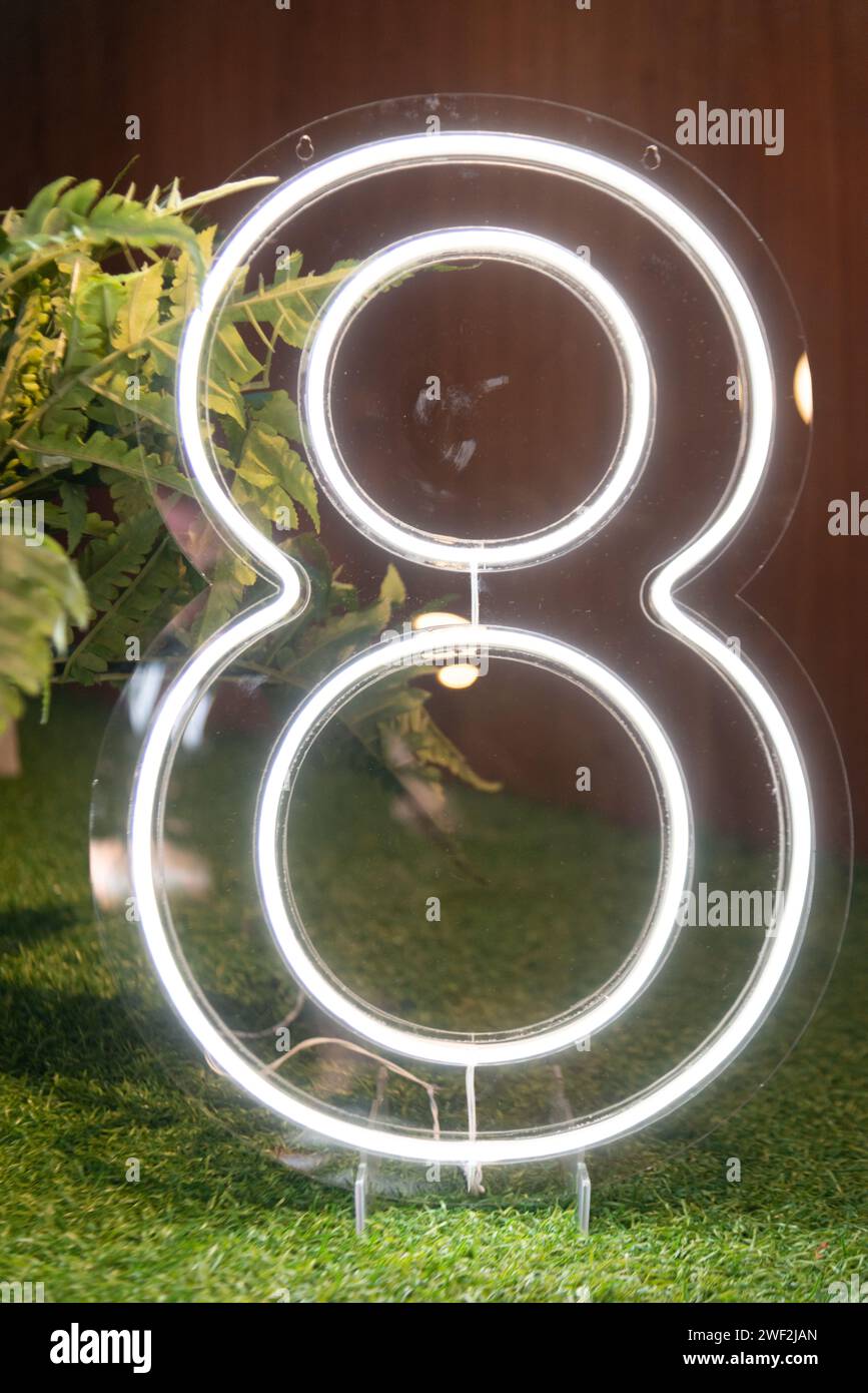 A brightly illuminated numeral sign stands gracefully amidst lush green ...